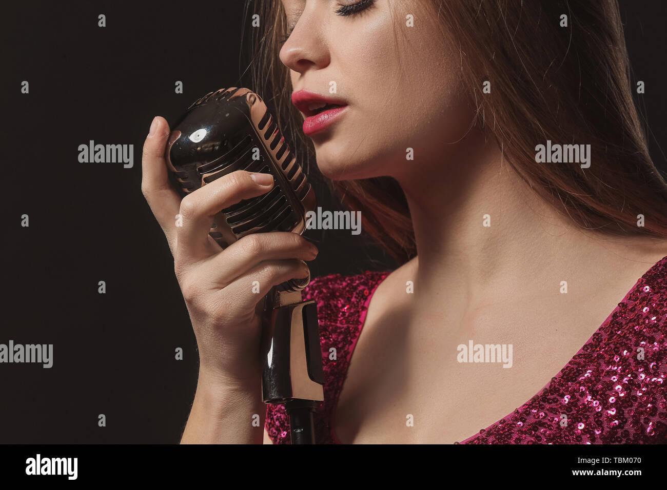 Beautiful female singer with microphone on dark background Stock Photo ...