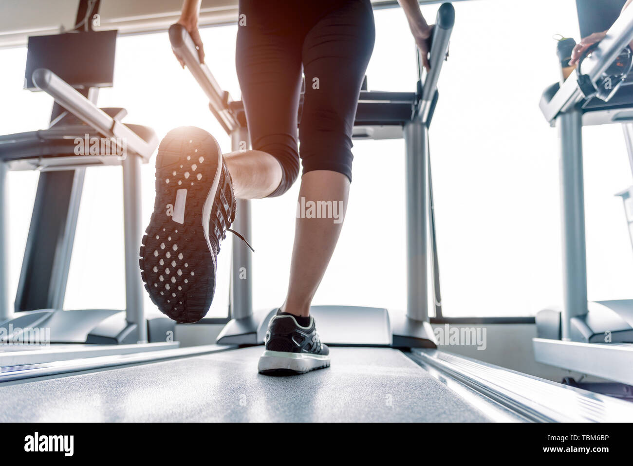 Lower body at legs part of Fitness girl running on running machine or ...