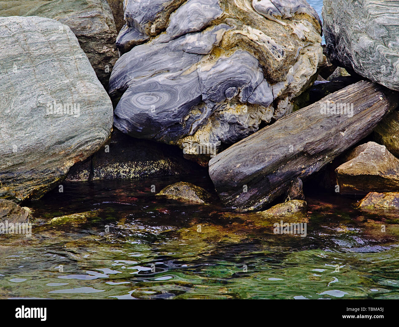 Nice textured rocks with cyclical patterns stacked above sea, Tinos ...