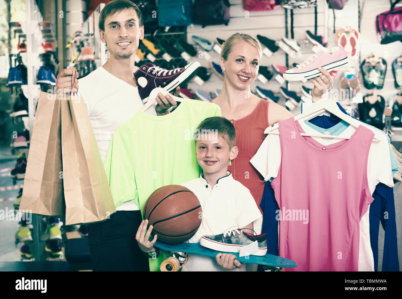 Friendly parents with boy in school age shopping clothing in sport ...