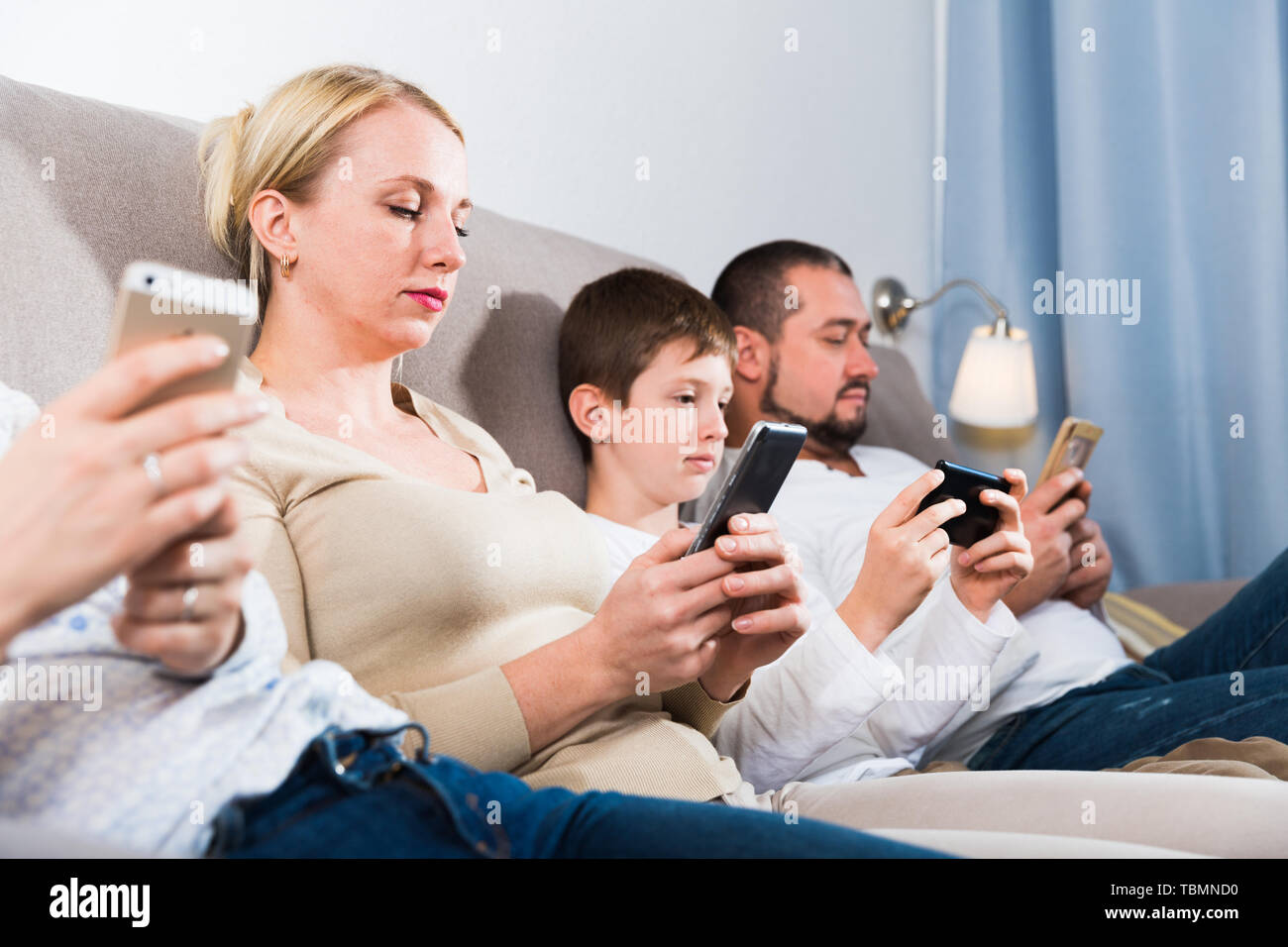 Parents and teen son using phones sitting on sofa at home Stock Photo ...
