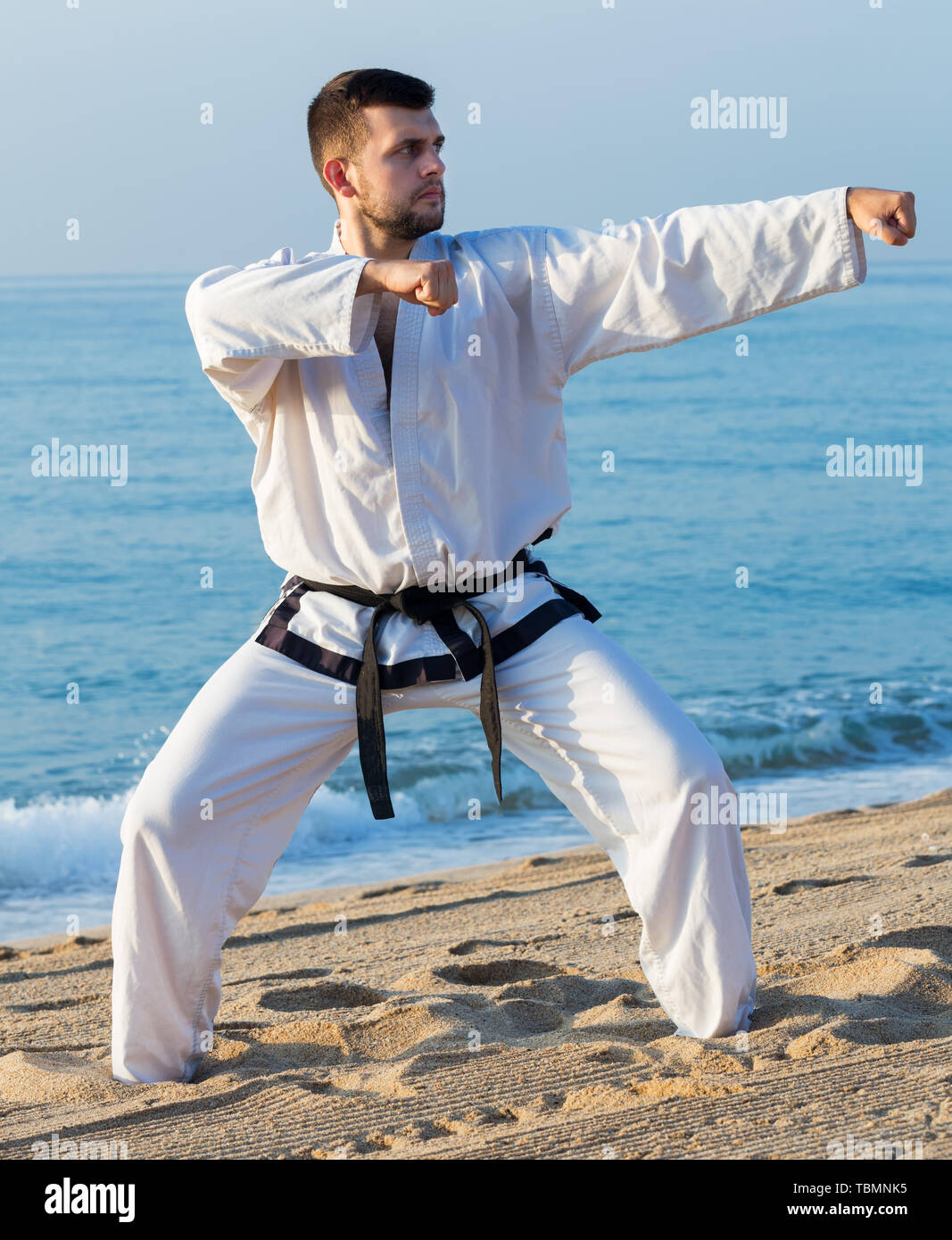 Young guy practising karate poses at beach in sunrise outdoor Stock ...