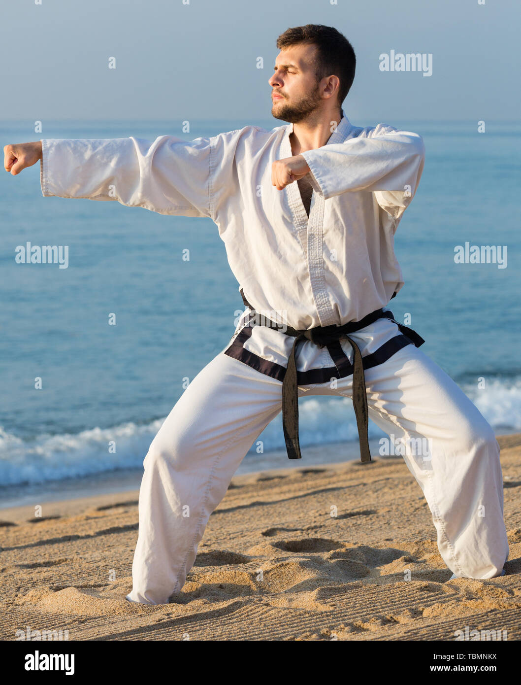young man practicing karate positions at ocean quay in sunset Stock ...
