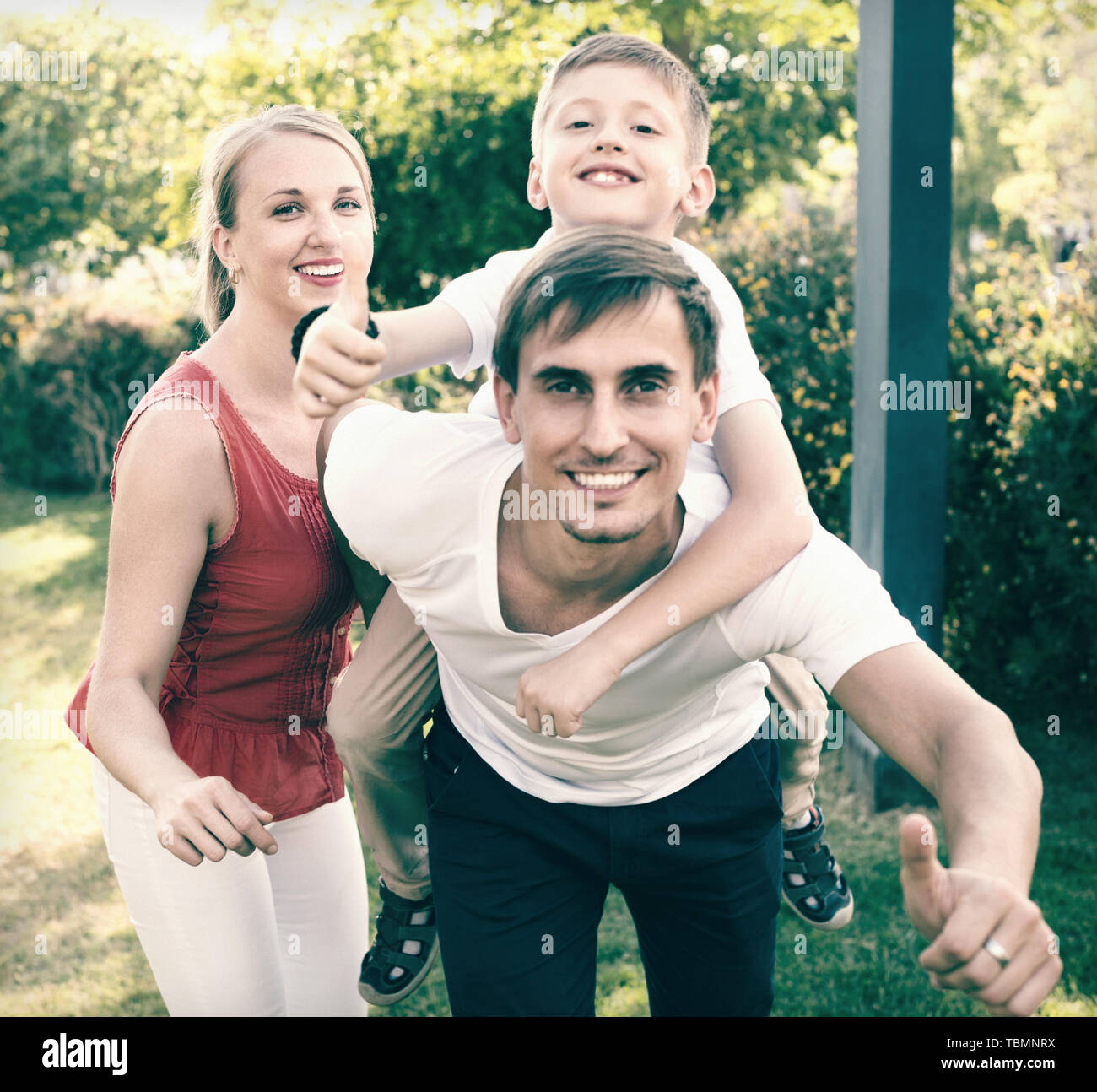 Portrait of cheerful smiling family with boy sitting on father's back ...