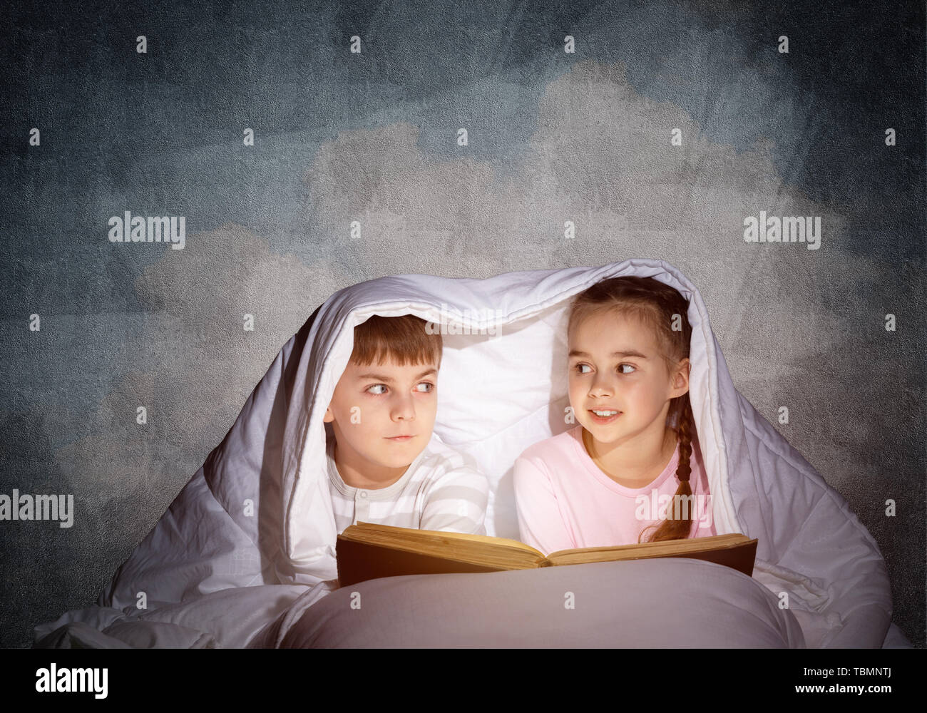 Engrossed little girl and boy reading book Stock Photo - Alamy