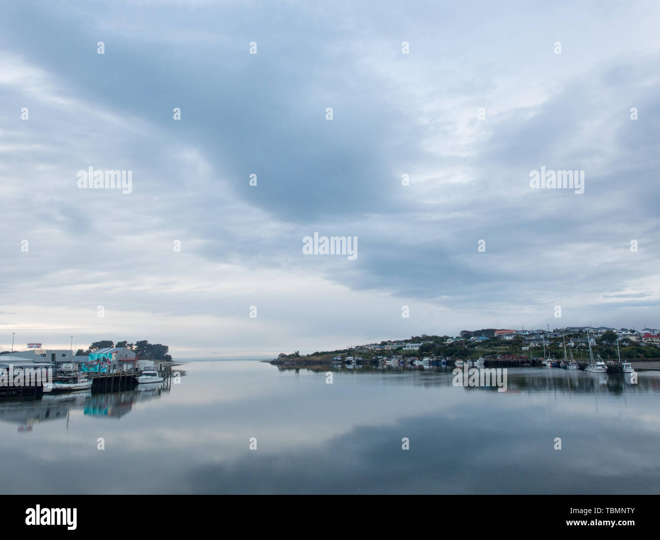 Fishing boats by the wharf, houses on the hill, gray sky above, calm ...