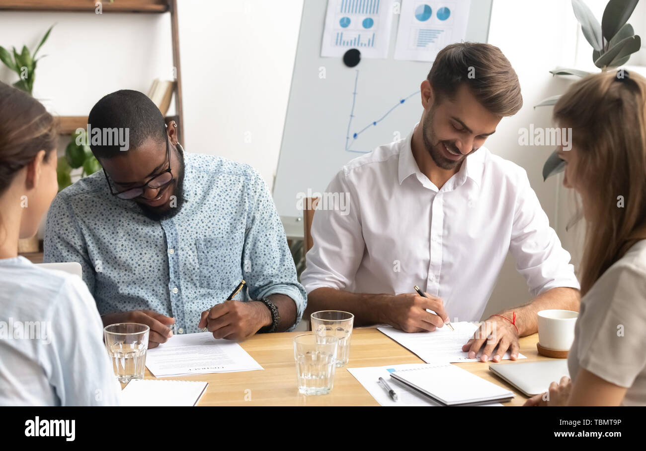 Happy smiling diverse businessmen putting signature on paper document ...