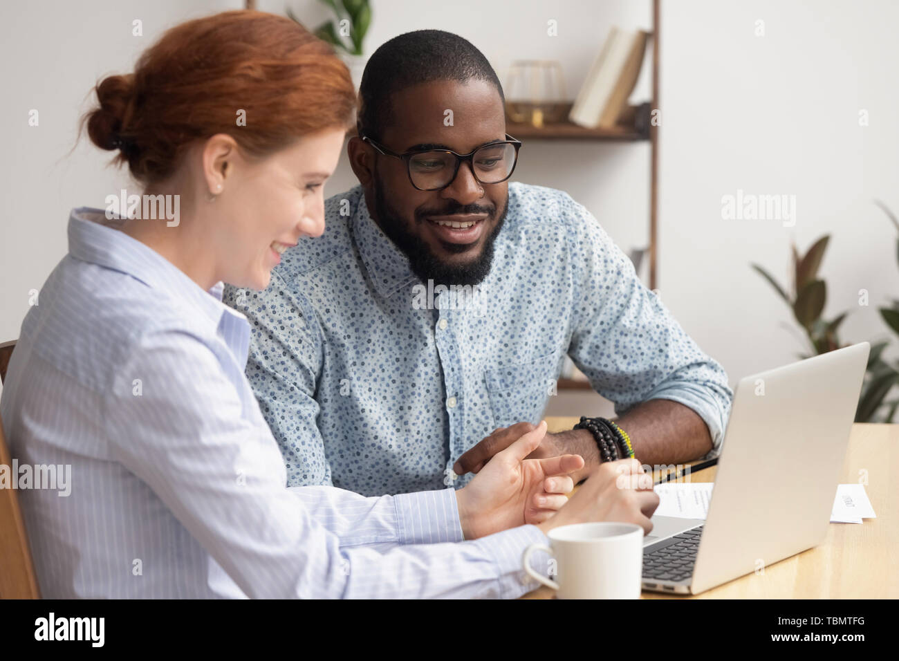 Two diverse laughing businesspeople watching funny video on laptop ...