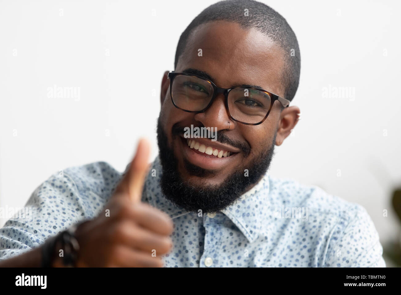 Portrait of smart smiling African American businessman gesturing thumbs ...