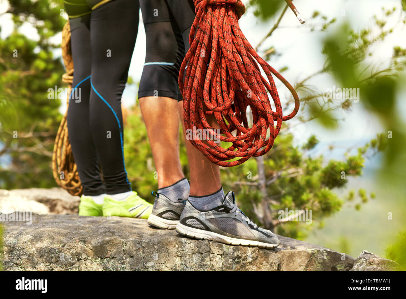 a couple of climbers with ropes on a cliff top. mountain climbing ...