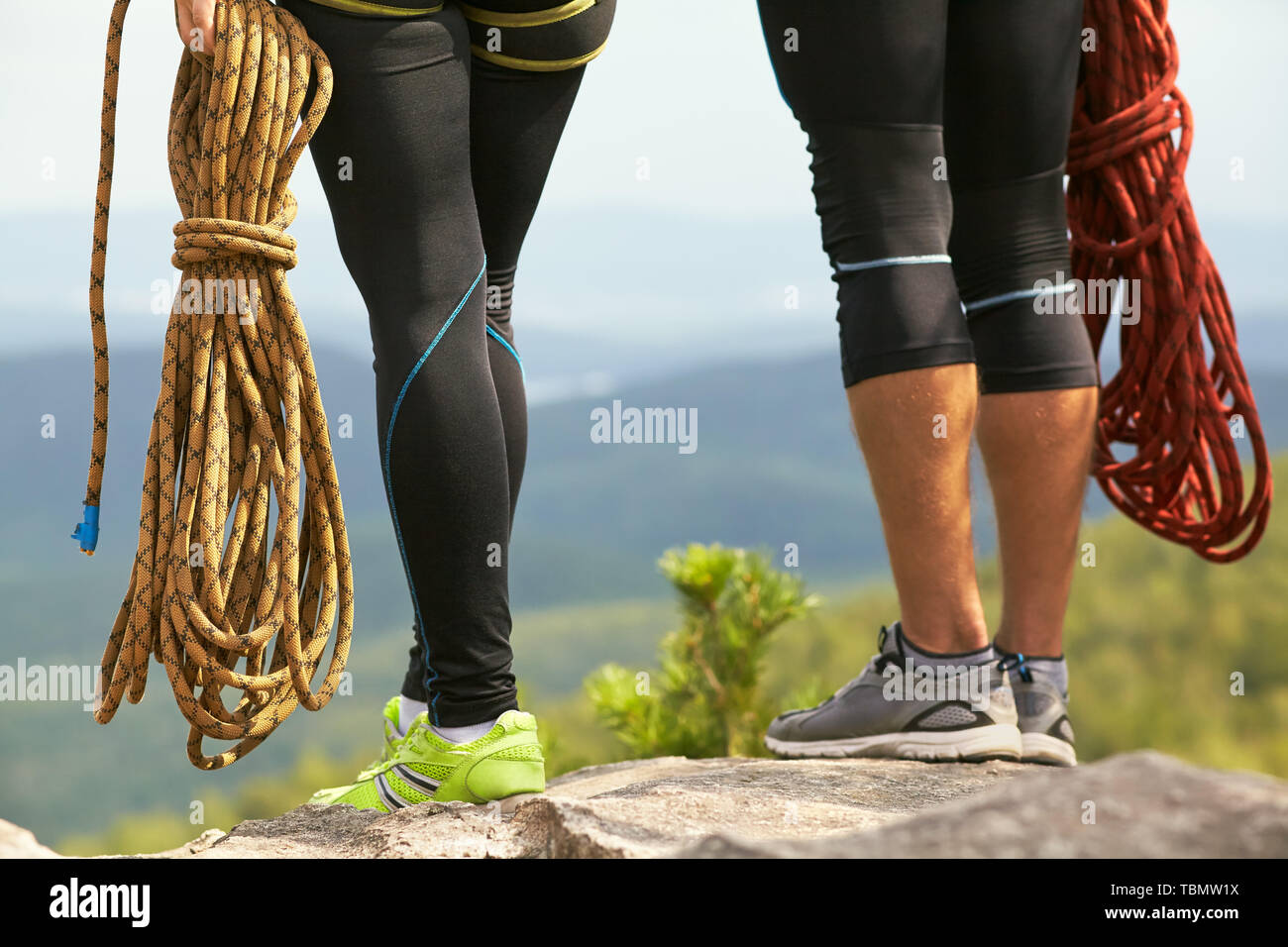 a couple of climbers with ropes on a cliff top. mountain climbing ...