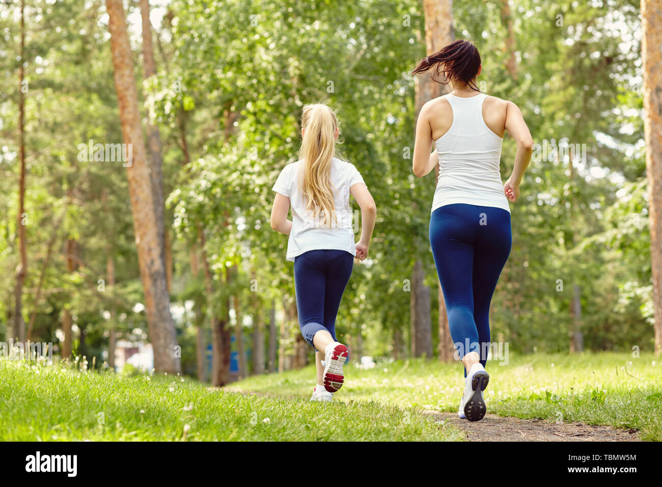 running sporty mother and daughter. woman and child jogging in a park ...
