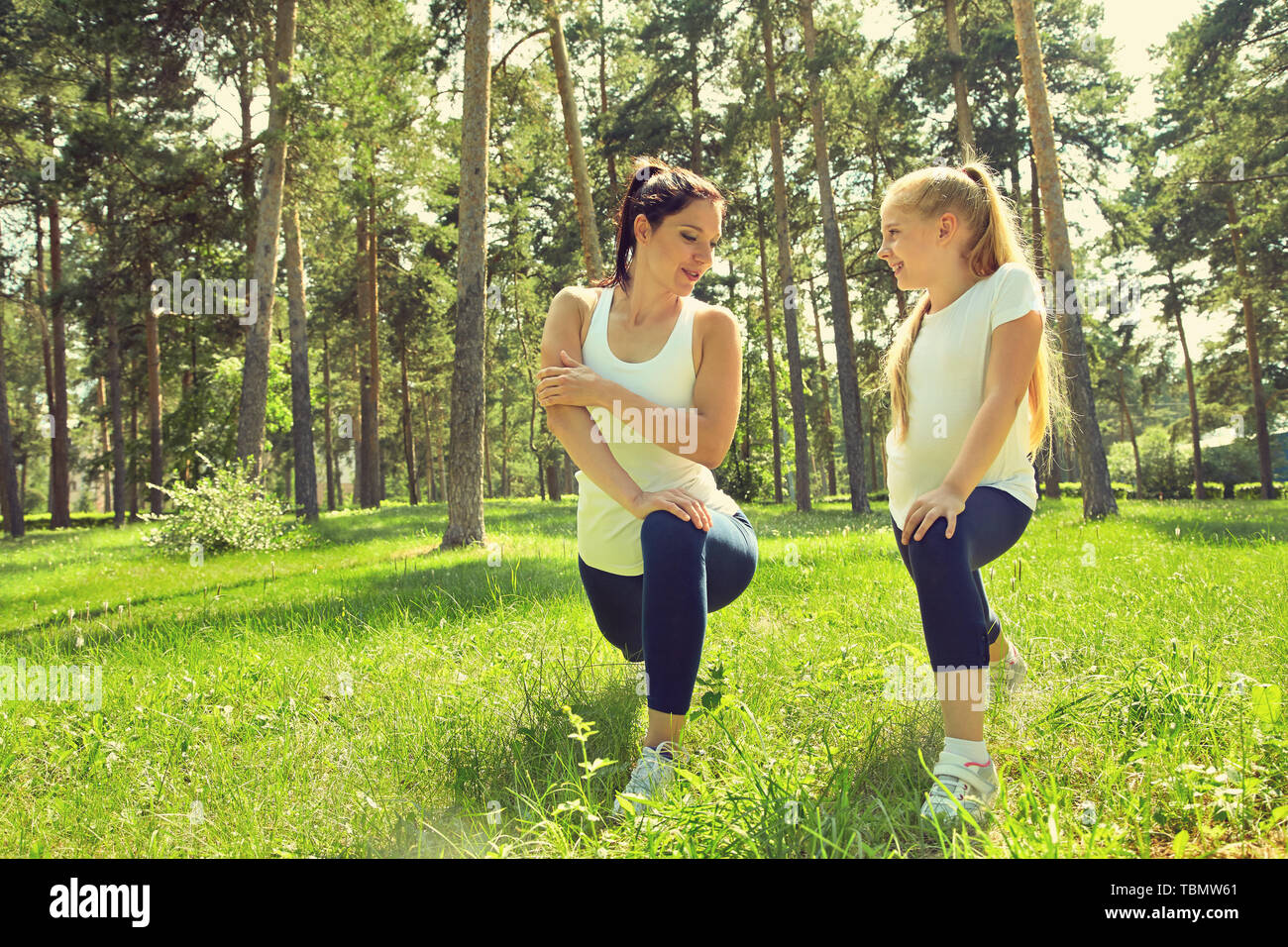sporty mother and daughter. woman and child training in a park. outdoor ...