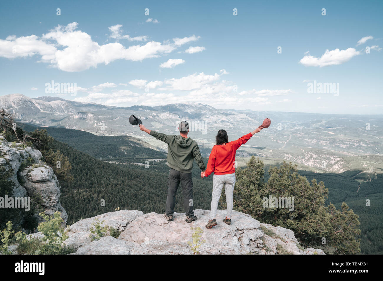 Hikers relaxing on top of a mountain and enjoying the view of valley ...