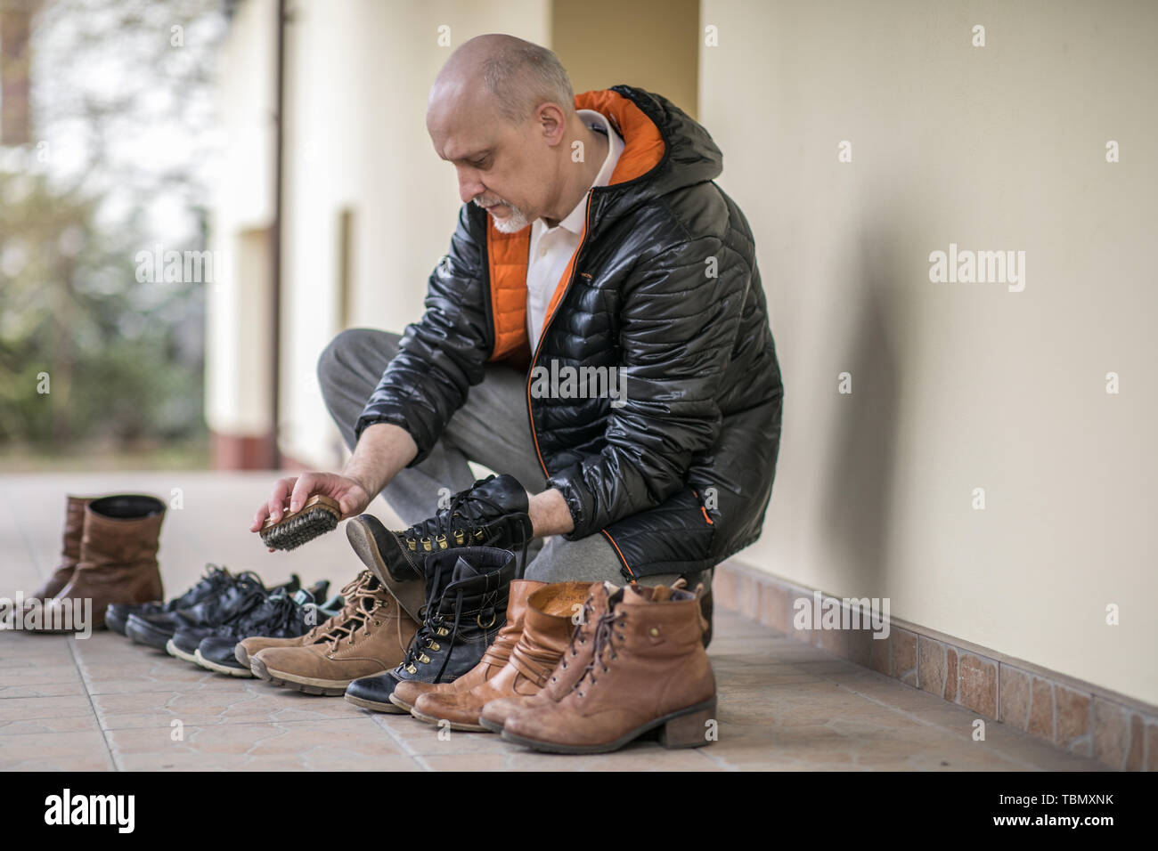 The man is polishing the shoes on the terrace during the spring time ...