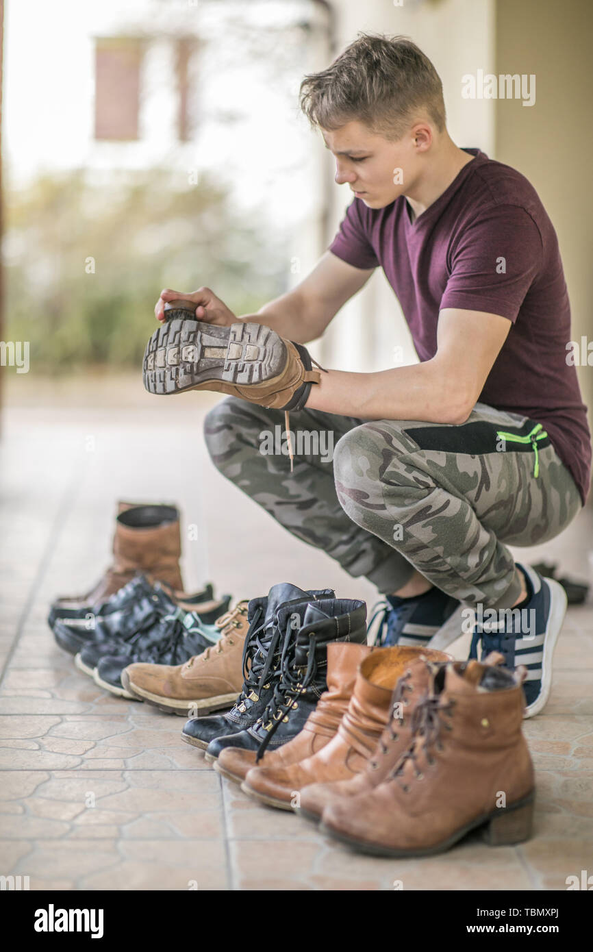 Young man is polishing the shoes on the terrace during the spring time ...