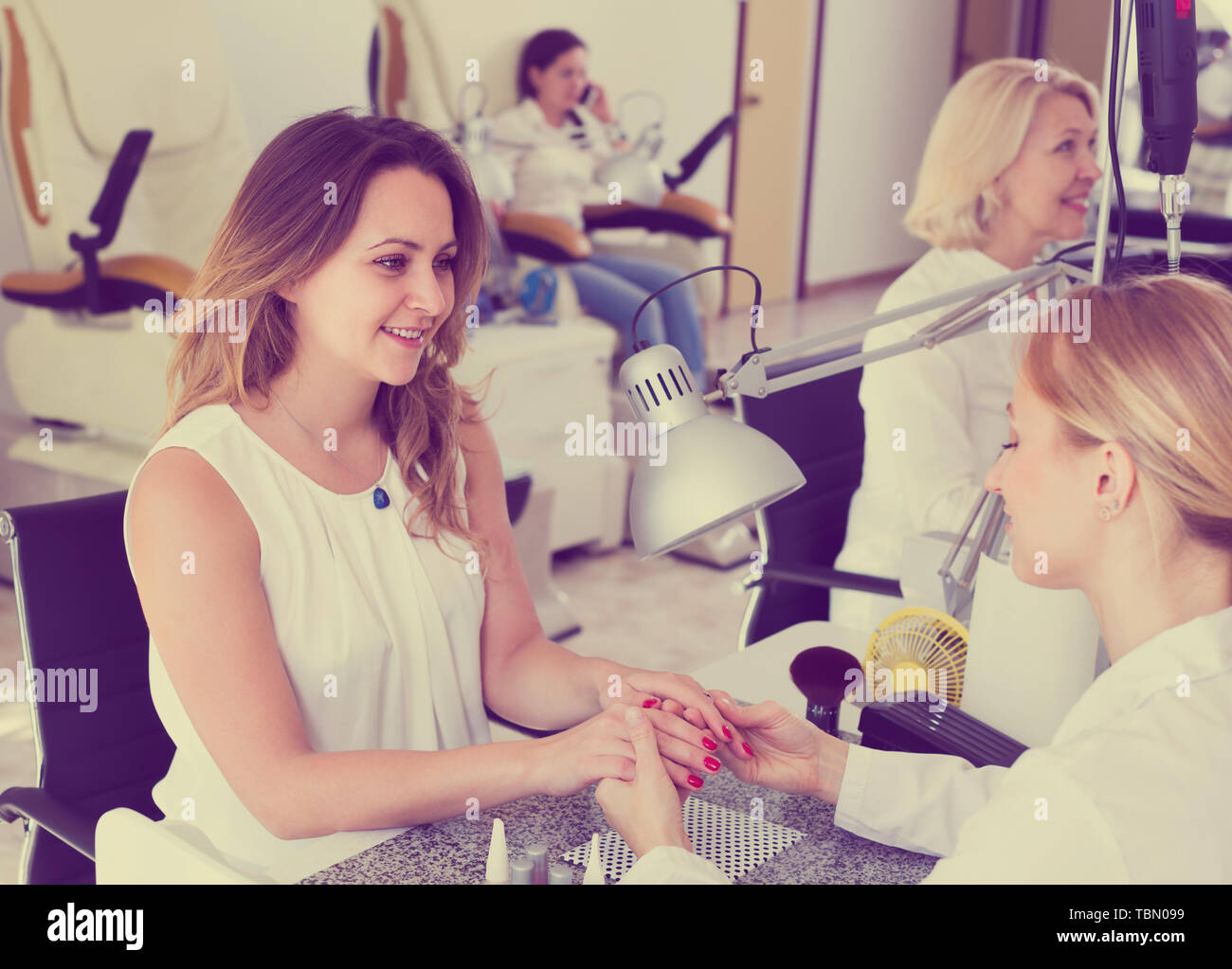 Cheerful women doing manicure in nail salon Stock Photo - Alamy