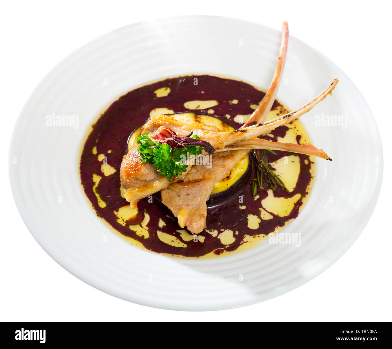 Roasted mutton ribs served with baked eggplant and wine sauce. Isolated ...