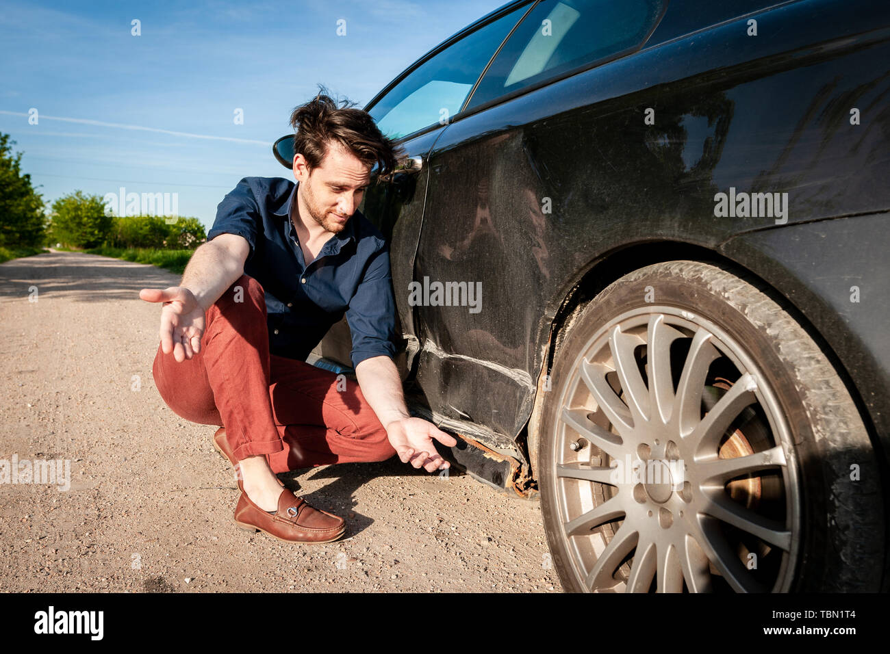 Angry man next to a car with damage on the left side and rotten sill on ...