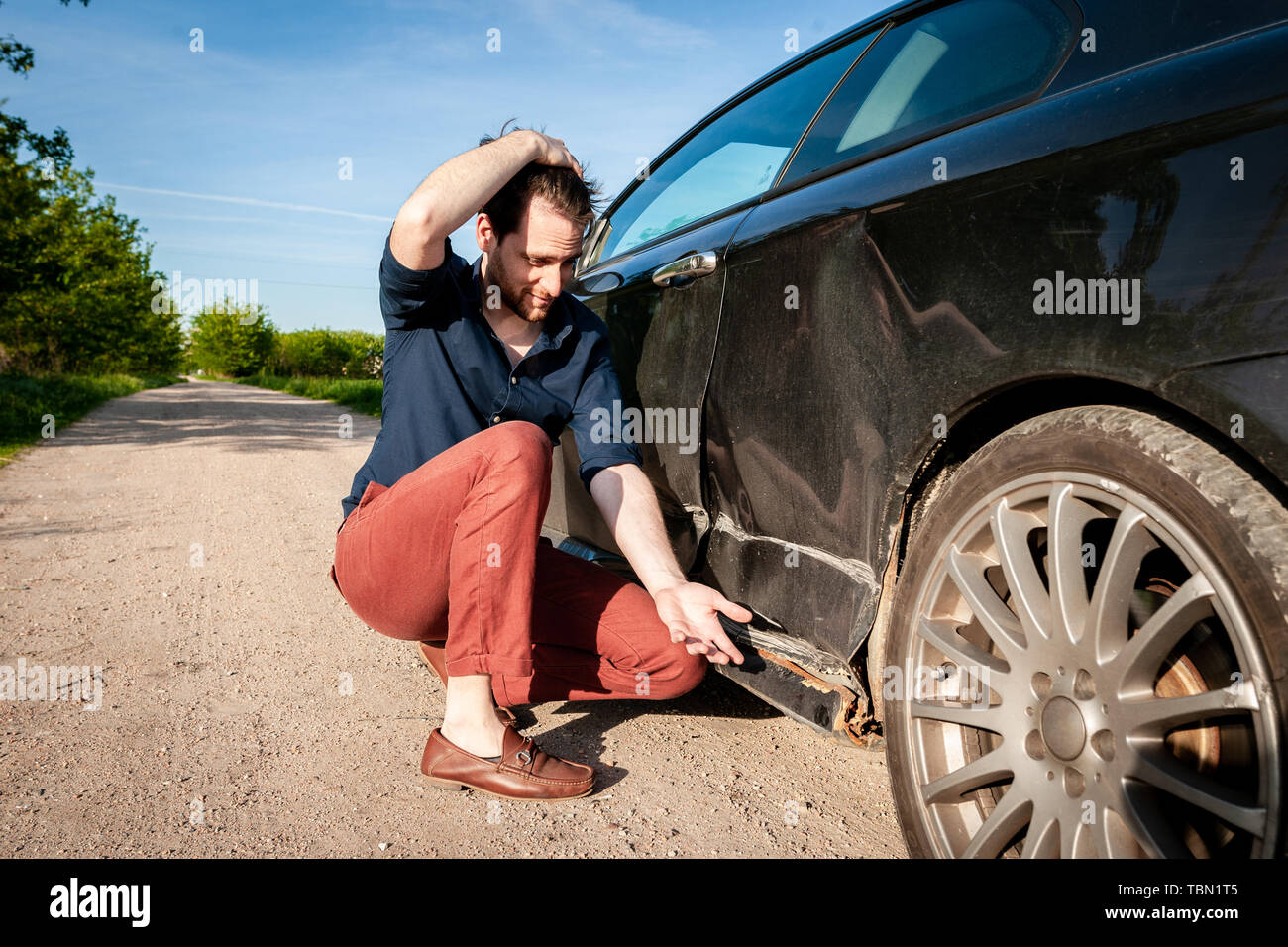 Angry man next to a car with damage on the left side and rotten sill on ...