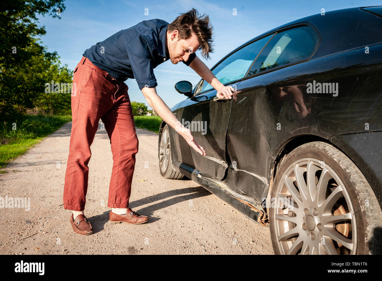Angry man next to a car with damage on the left side and rotten sill on ...