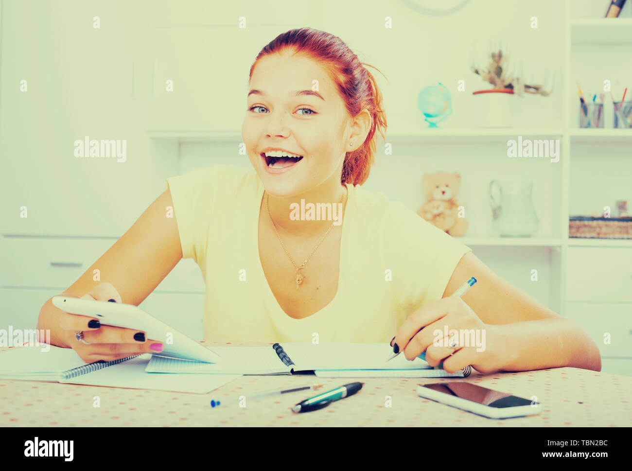 positive teenager girl taking notes while studying at home Stock Photo ...