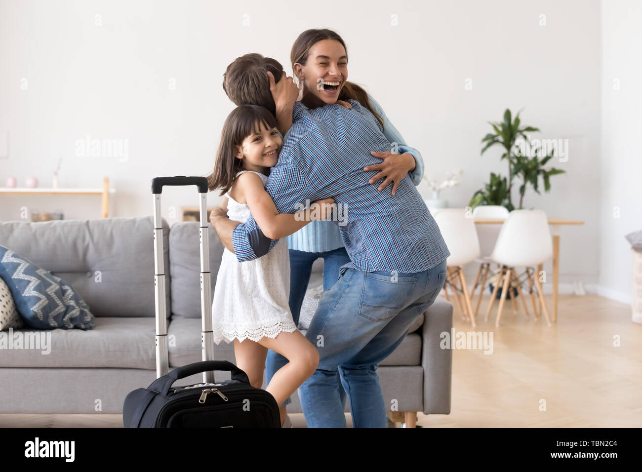 Excited mom and daughter hug welcome father home Stock Photo - Alamy