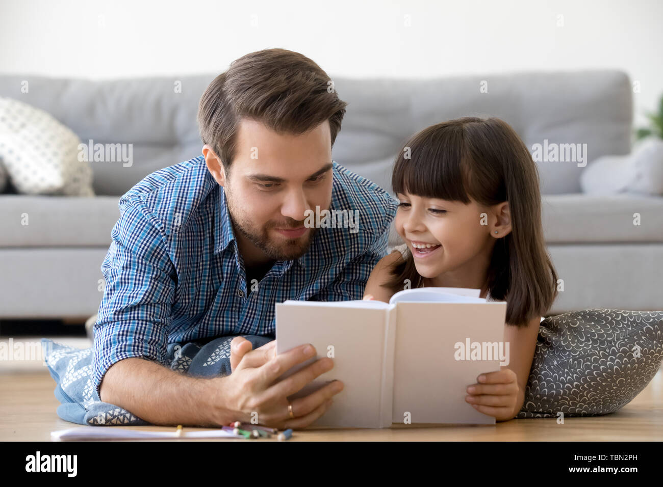 Caring dad lying on floor enjoy reading with little daughter Stock ...