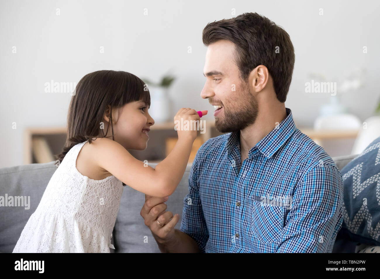 Funny little girl do makeup paint lips for young dad Stock Photo - Alamy