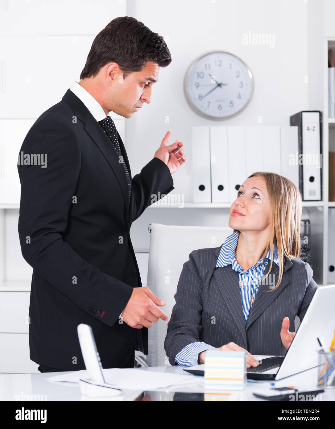 Angry boss blowing up female subordinate for being late Stock Photo - Alamy