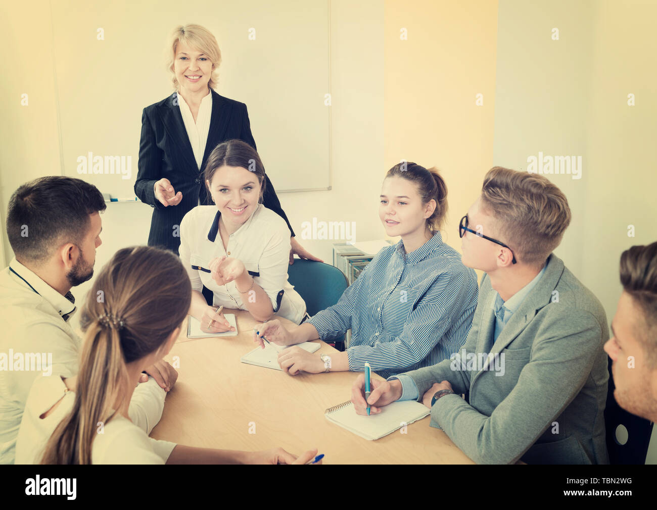 Group of attentive students and their female professor working together ...