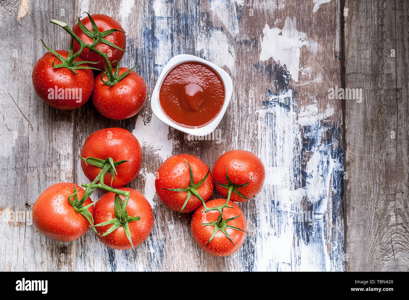 Fresh tomatoes on a branch and tomato sauce on a rustic background ...