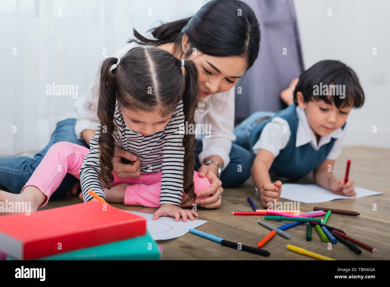 Mother teaching children in drawing class. Daughter and son painting ...