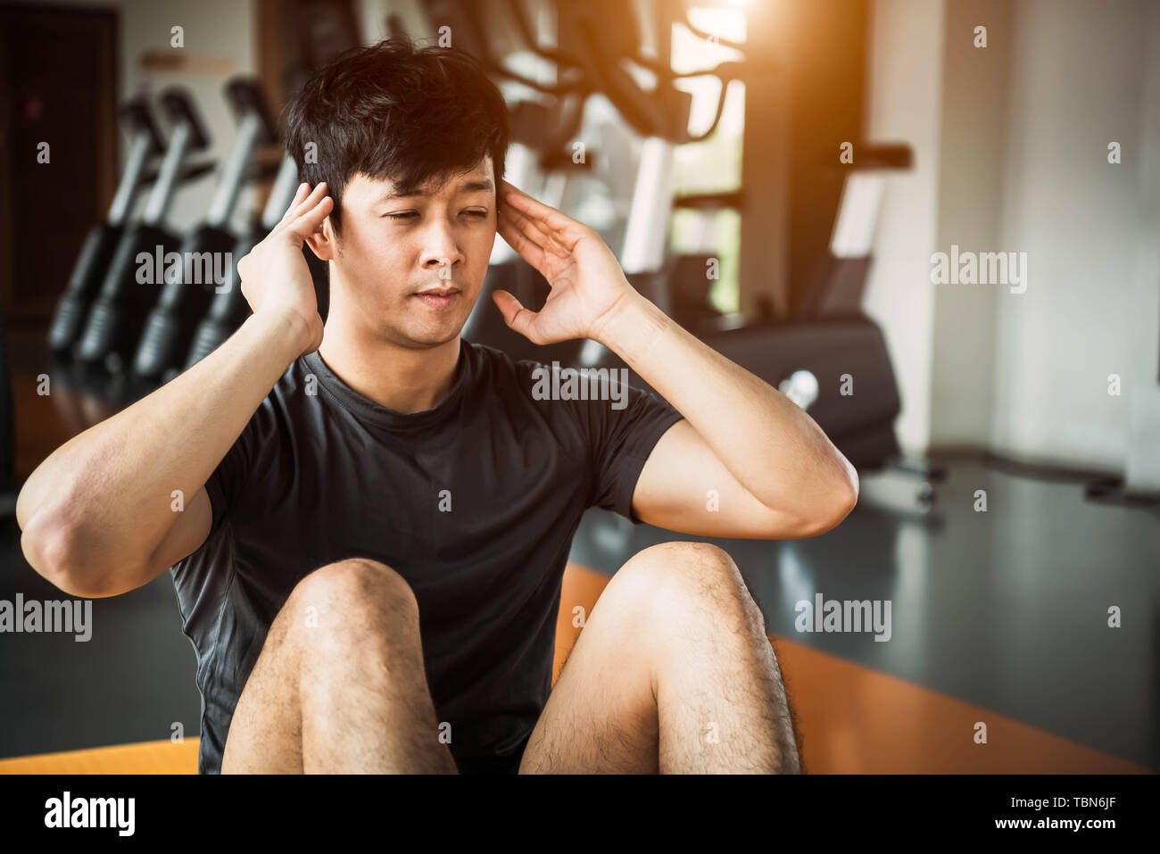 Asian sport man doing crunch or sit up posture on yoga mat in fitness ...