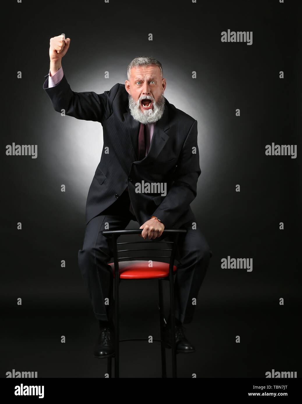Angry mature businessman on dark background Stock Photo - Alamy