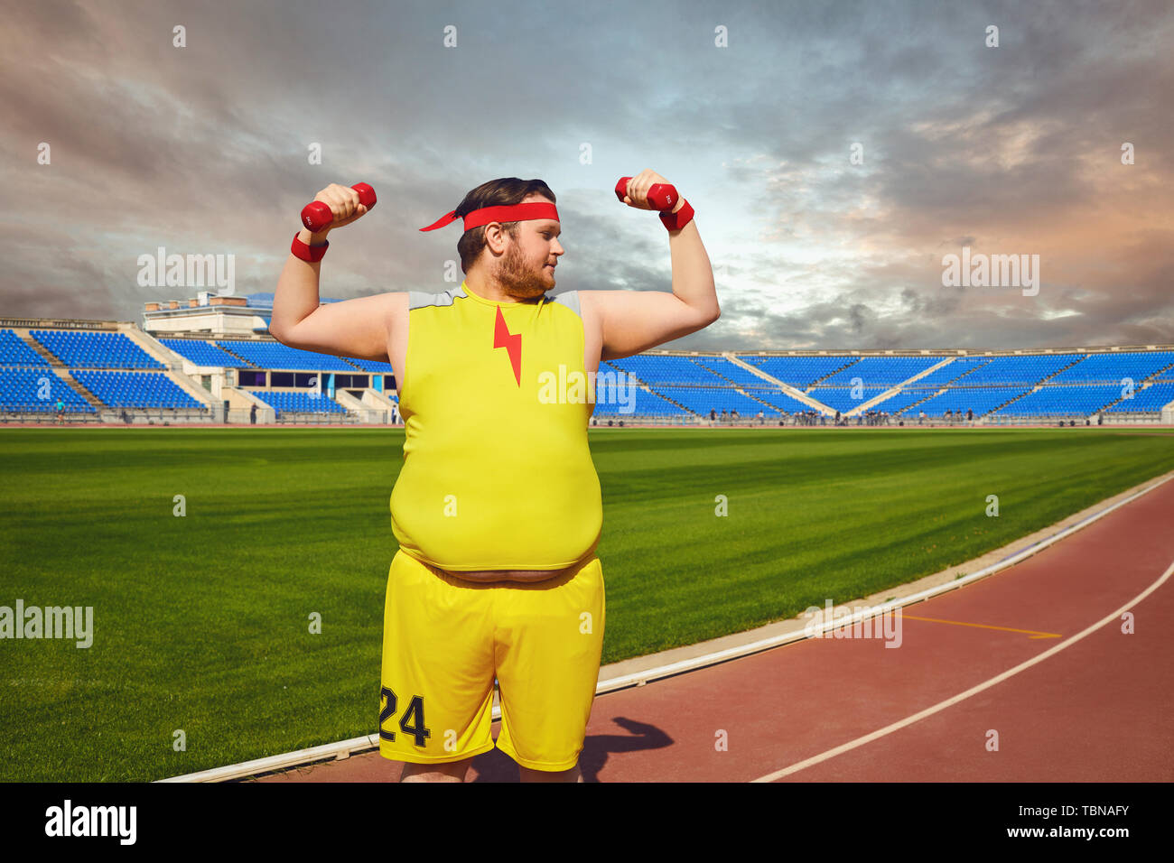 Fat man in yellow sportswear with dumbbells in his hands playing sports ...