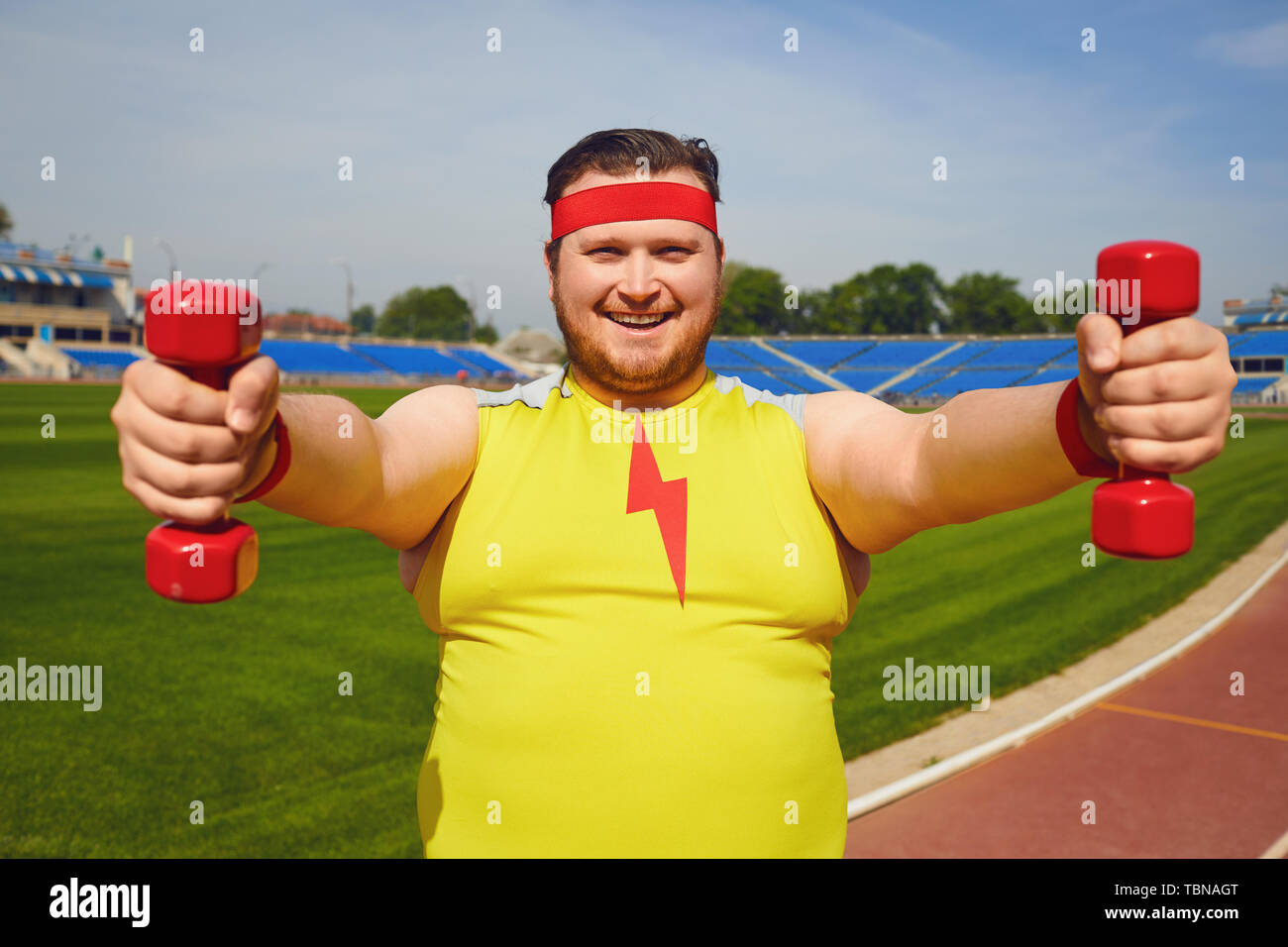 Fat man in yellow sportswear with dumbbells in his hands playing sports ...