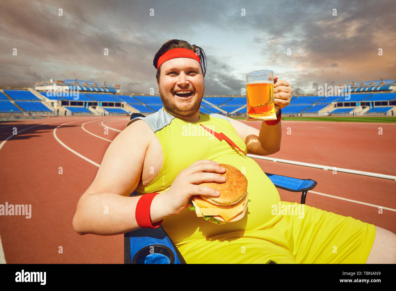 Fat man eating a burger and beer while sitting in training at the ...