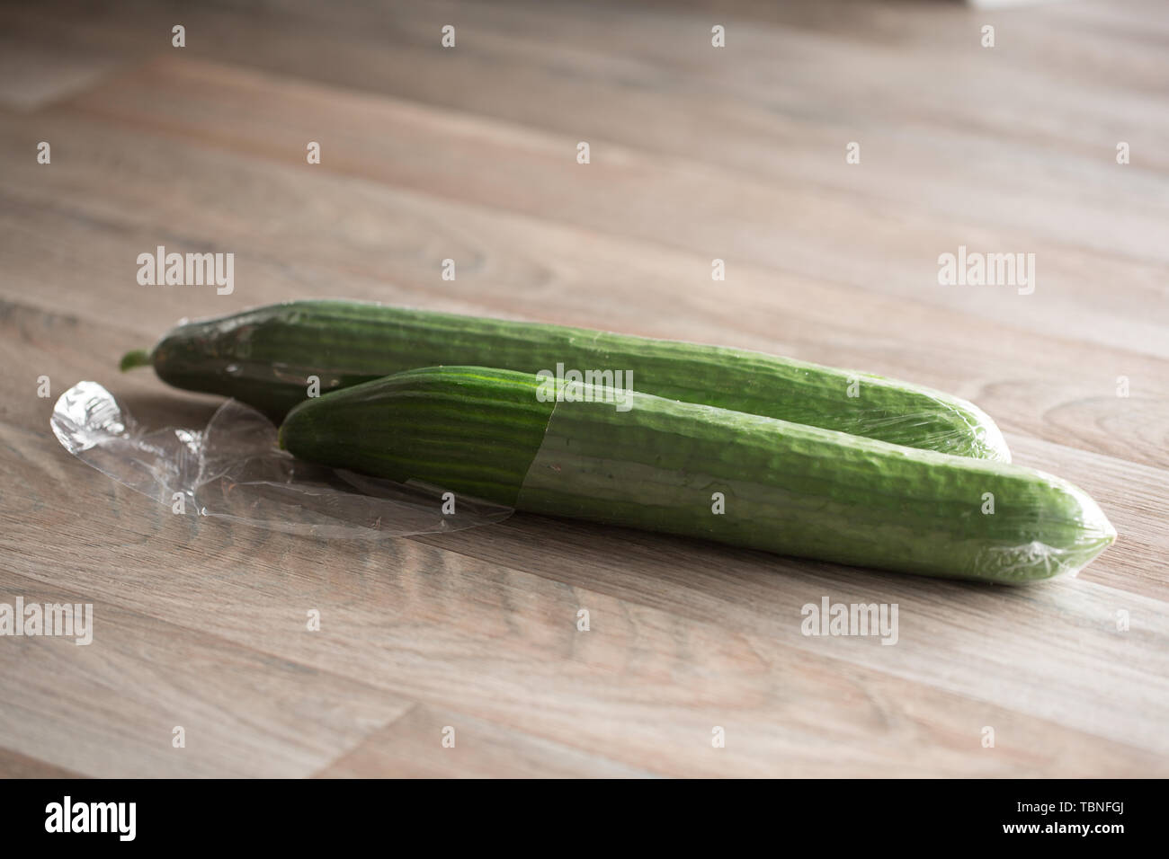 Tear open a plastic-wrapped cucumber Stock Photo - Alamy