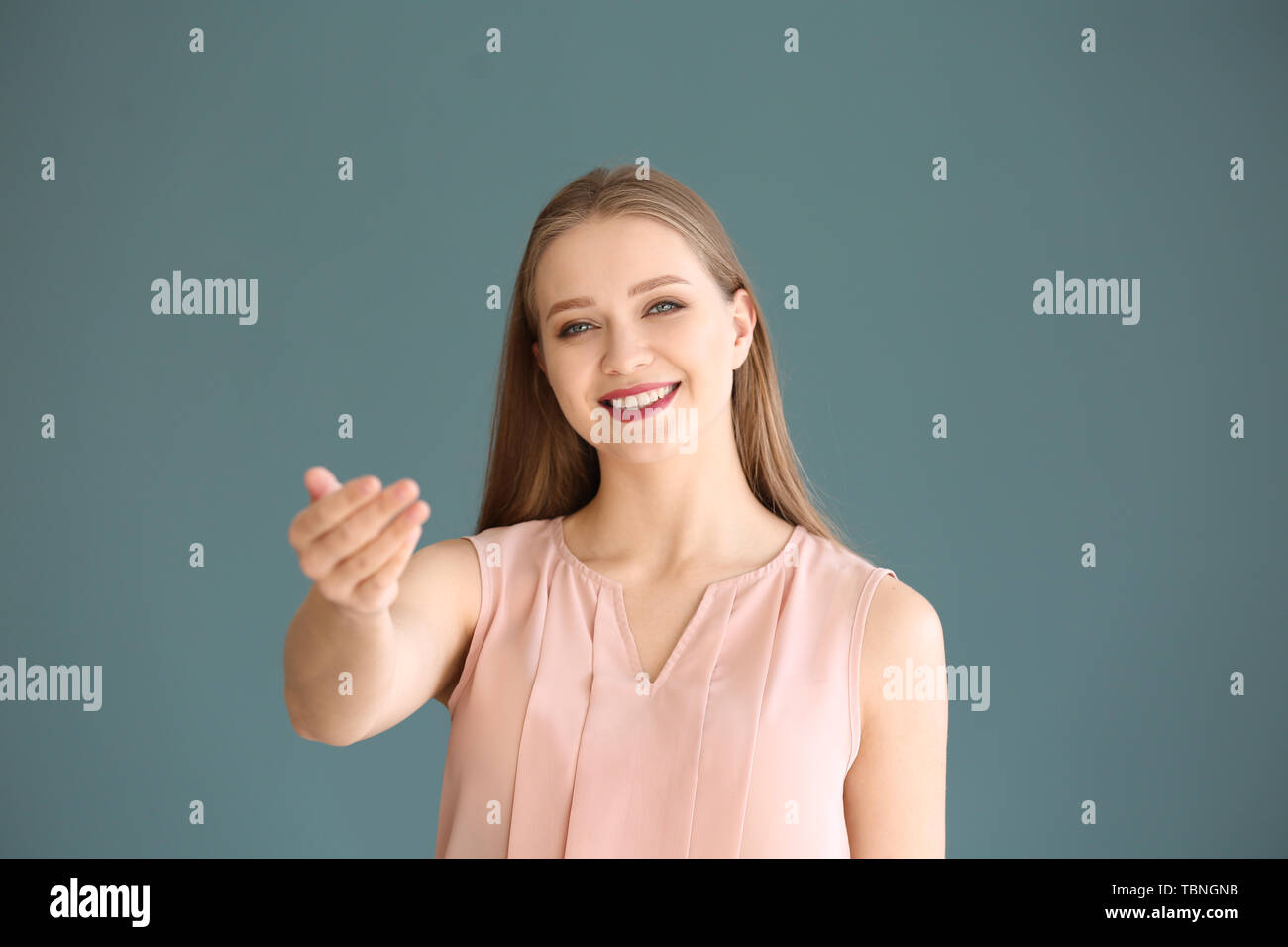 Beautiful young woman inviting viewer against grey background Stock ...