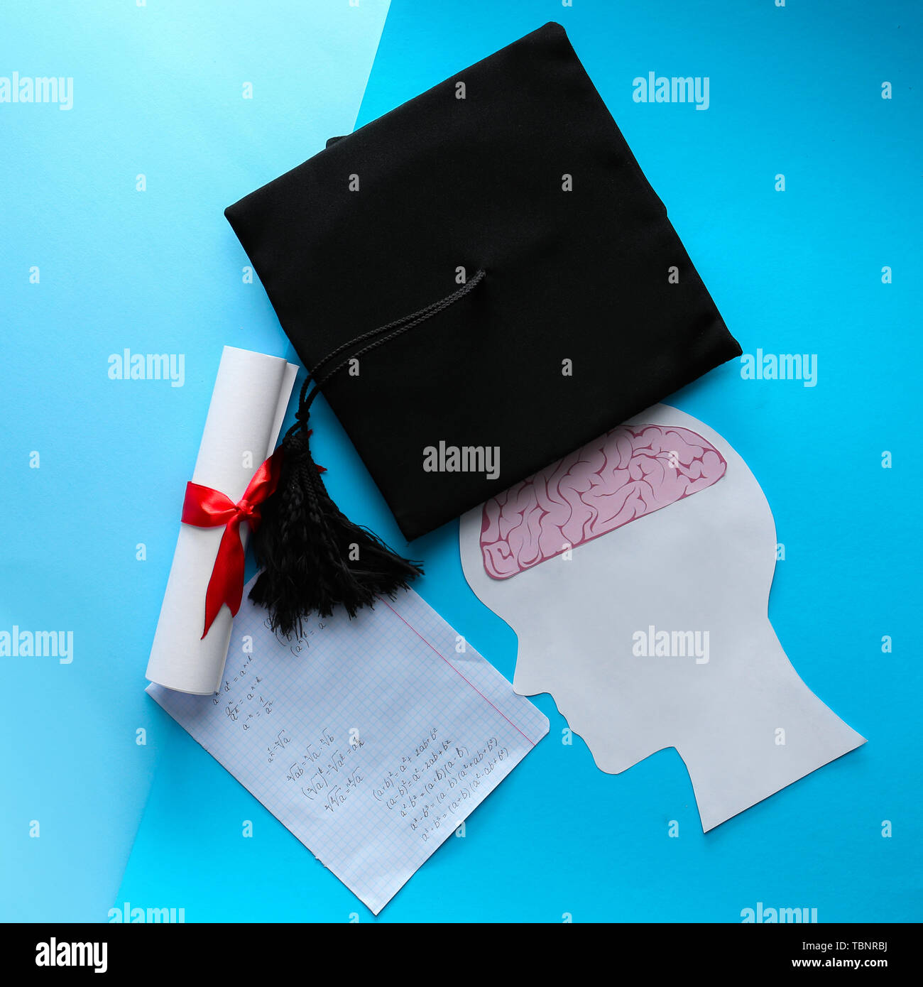 Mortar board with diploma, human head with brain and sheet of paper on ...