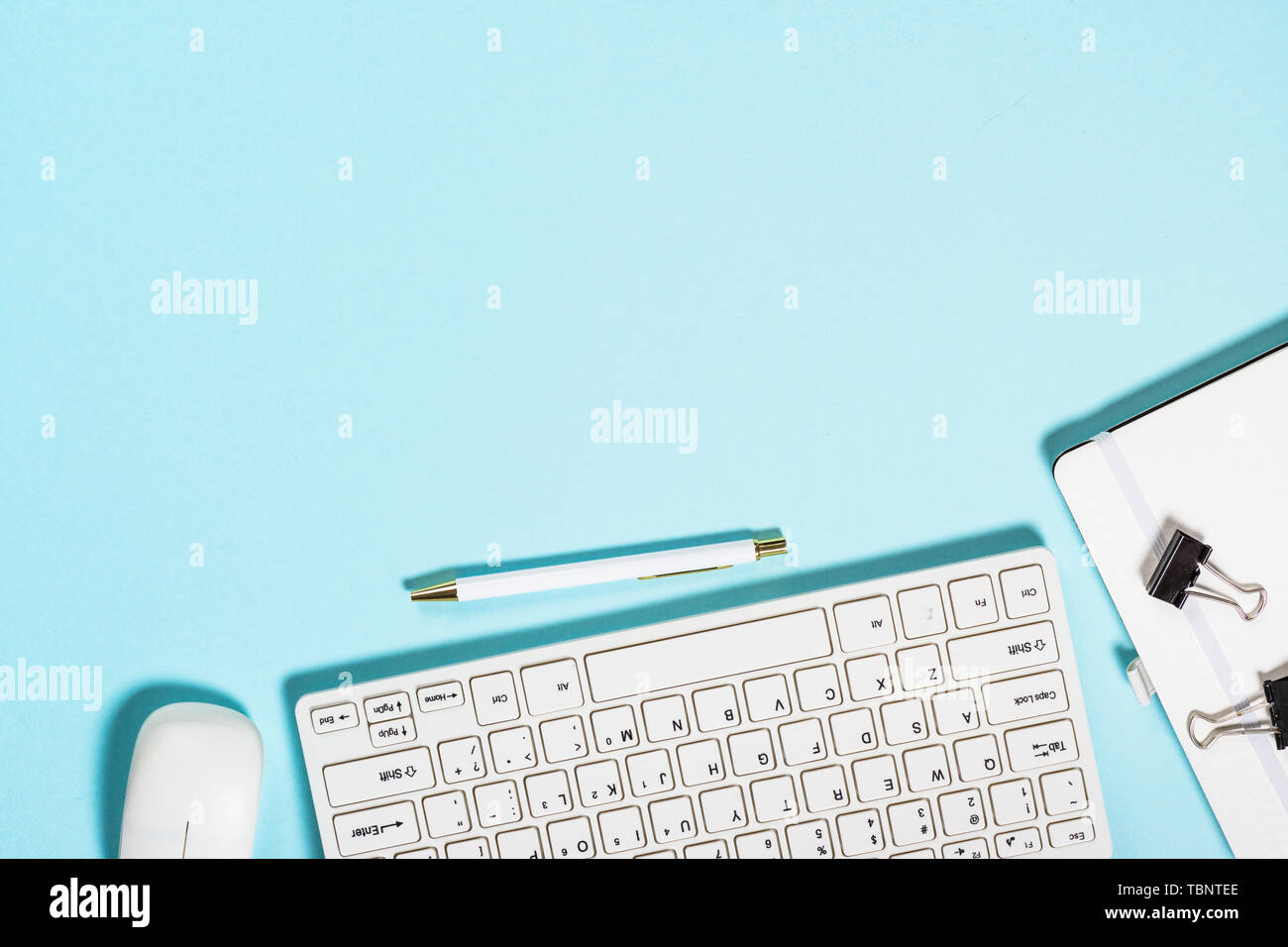 Office desk with keyboard and notebook on blue Stock Photo - Alamy