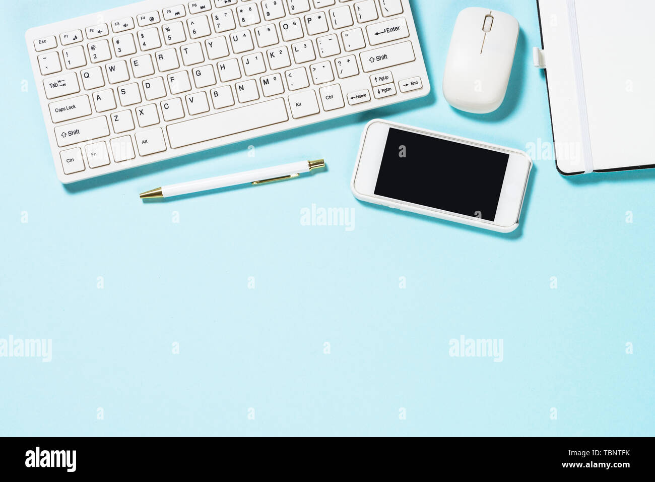 Office desk with keyboard and notebook on blue Stock Photo - Alamy