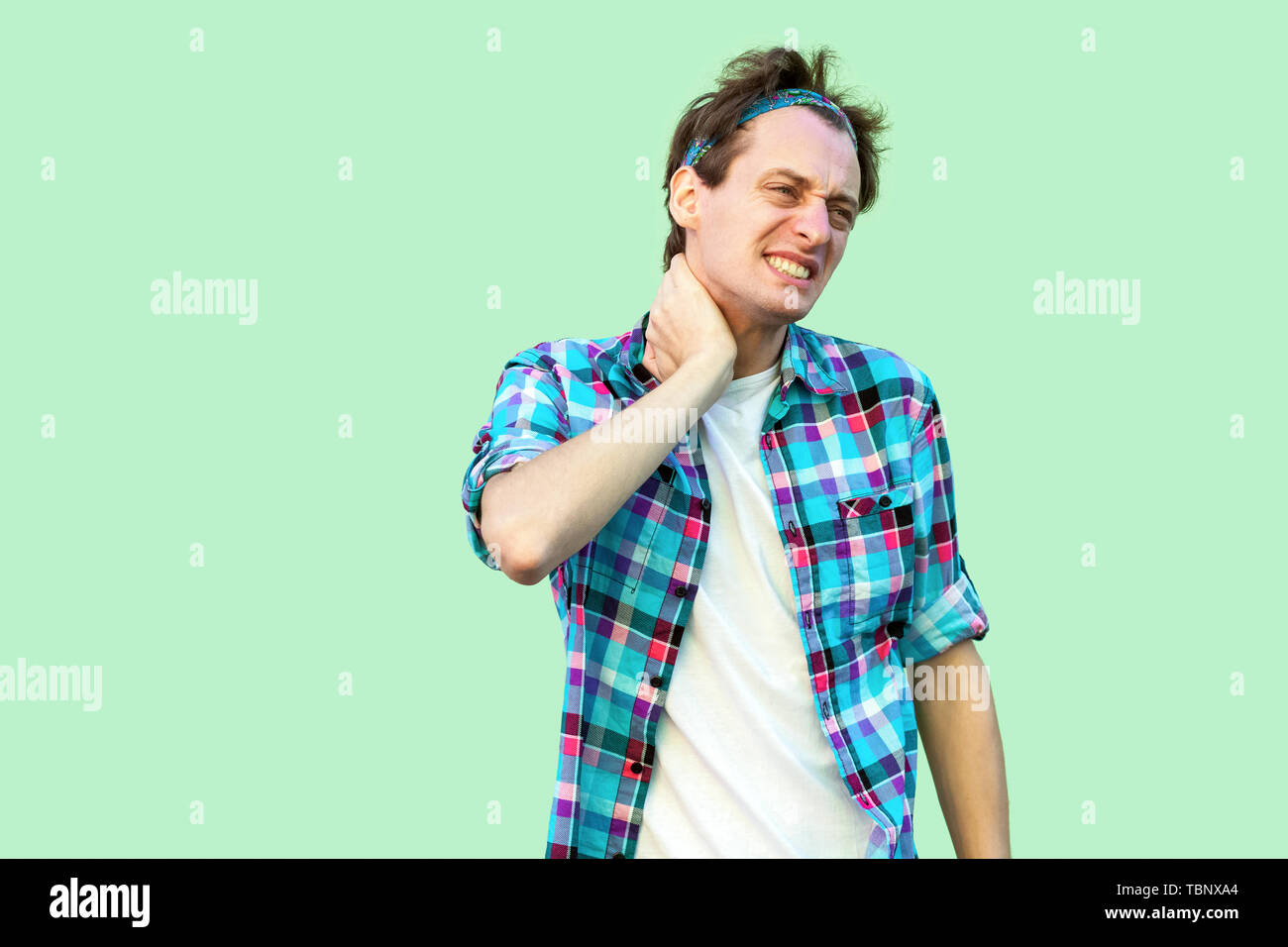 Neck or back pain. Portrait of sad injuried young man in casual blue ...