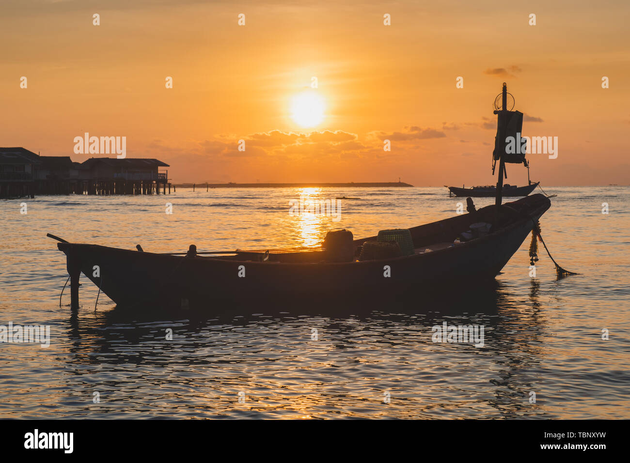 Wooden fishery boat floting on the sea with sunset time low lighting ...