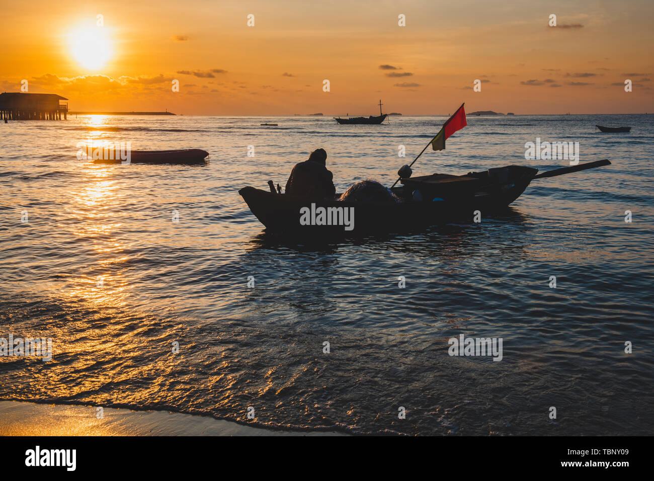 Wooden fishery boat floting on the sea with sunset time low lighting ...