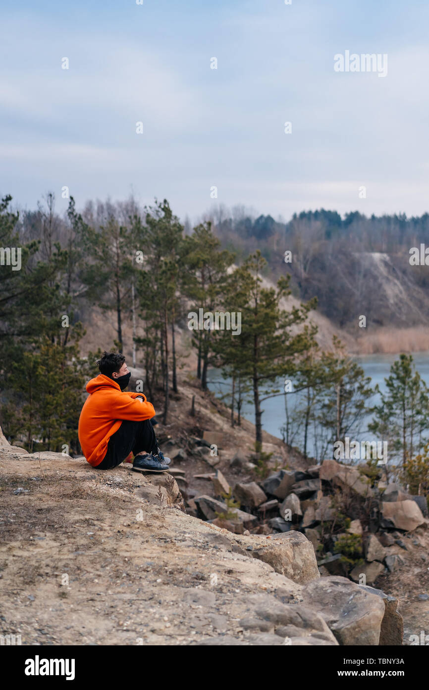 A young man sitting on the edge of a cliff poses for the camera Stock ...