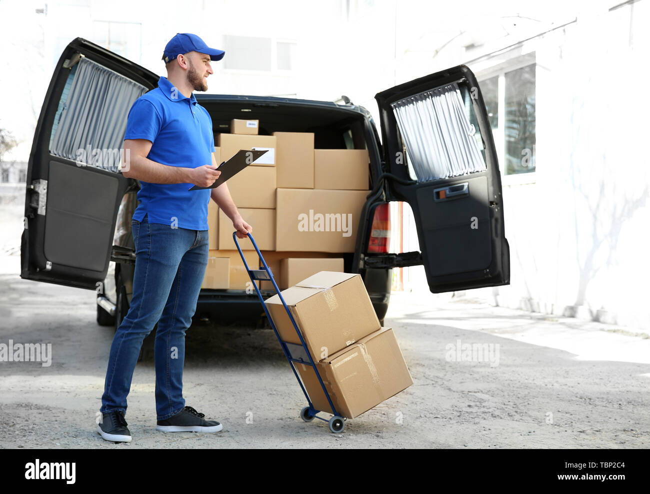 Handsome delivery man near car with parcels outdoors Stock Photo - Alamy