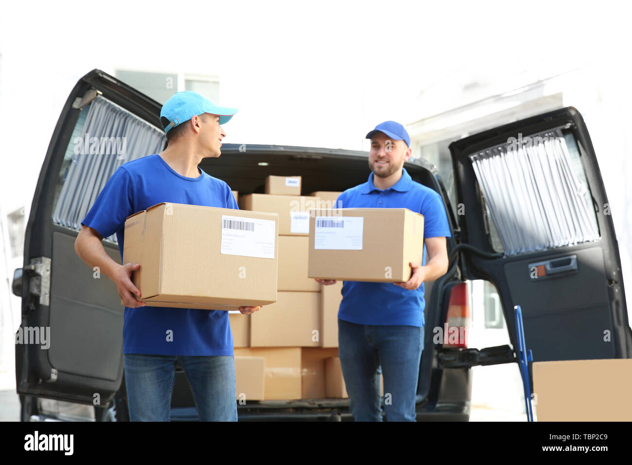 Delivery men carrying boxes to client Stock Photo - Alamy