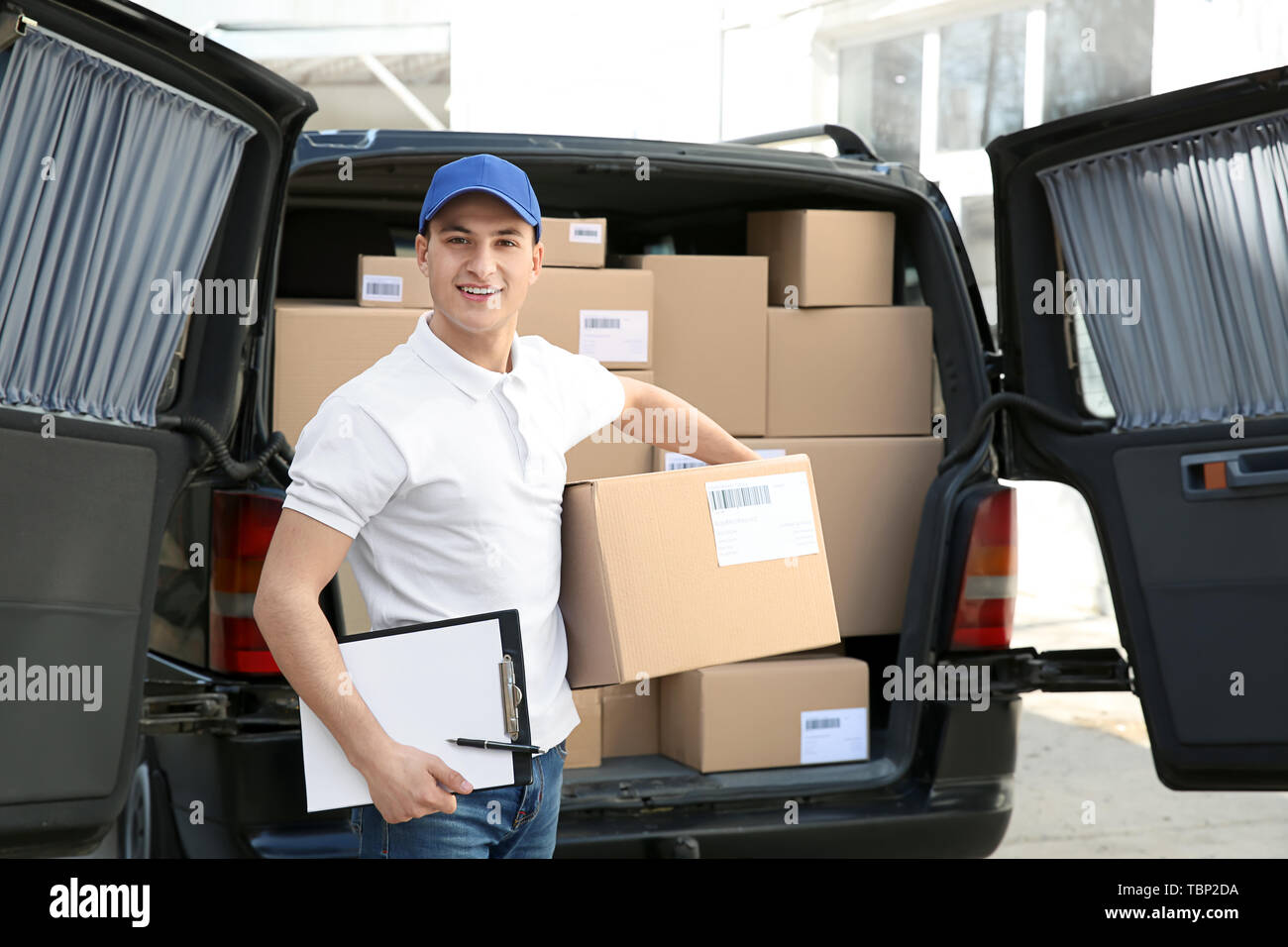Handsome delivery man near car with parcels outdoors Stock Photo - Alamy